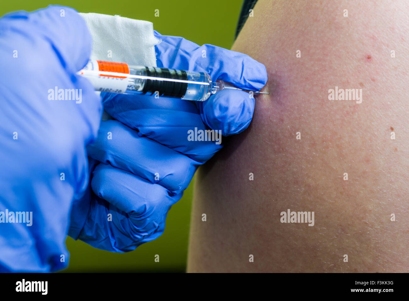 A injection of fluid medicine into a patients arm is done by two hands ...