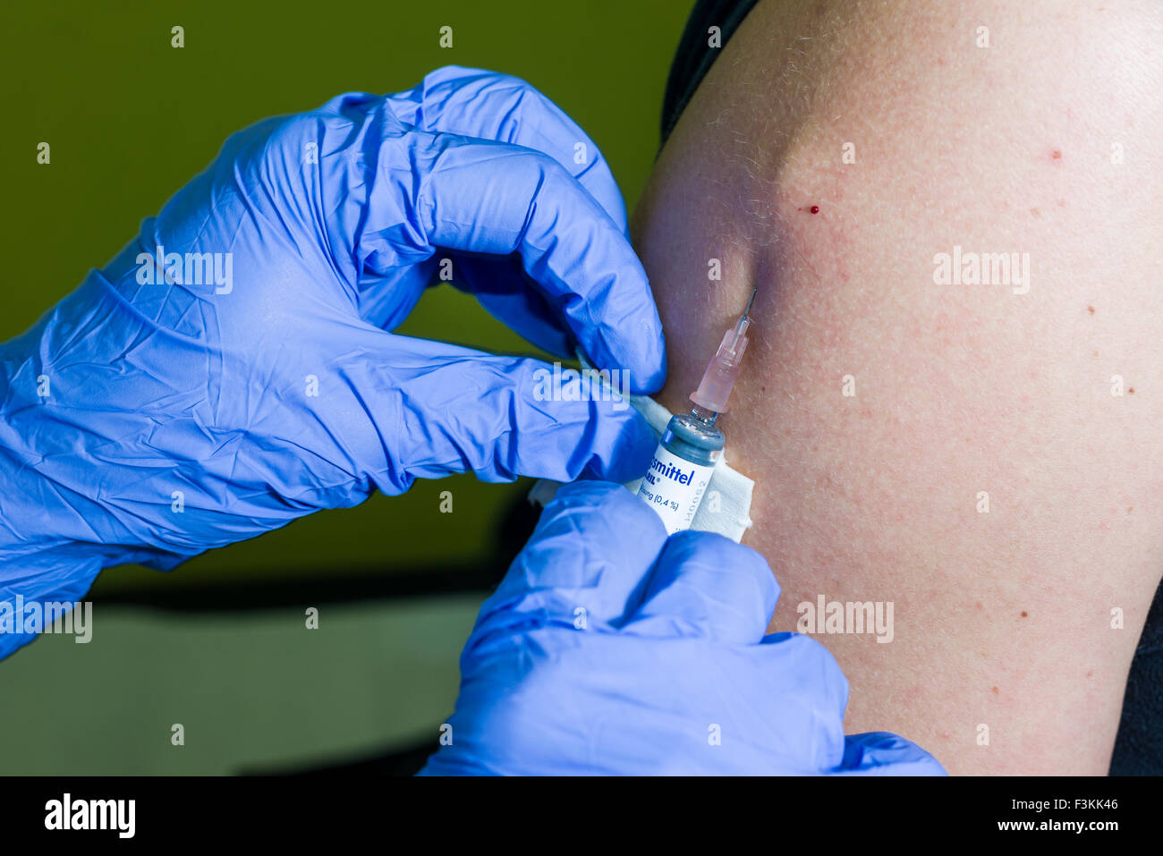 A injection of fluid medicine into a patients arm is done by two hands ...