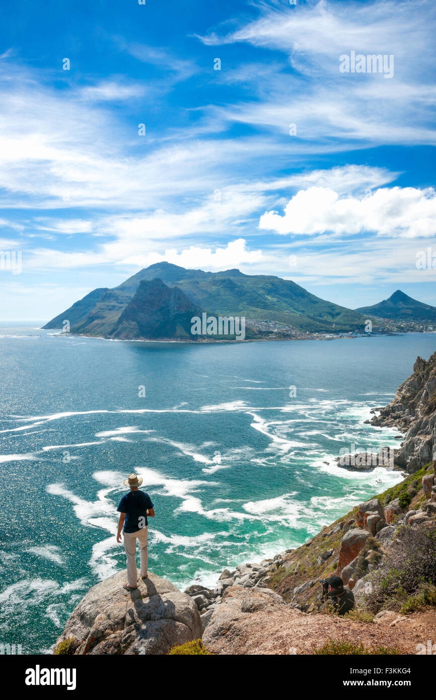 A lone hiker standing on rock above Atlantic Ocean looks out toward ...