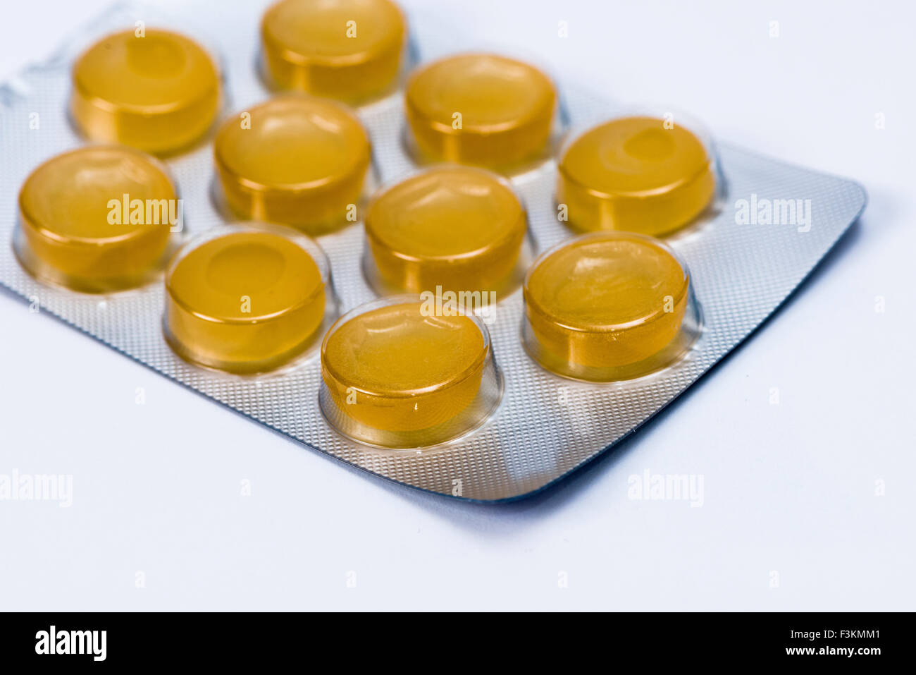 A filmstrip with yellow golden medicine tablets, displayed on a white ...