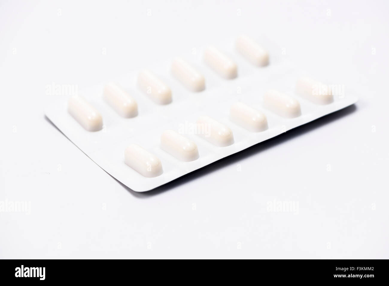 A white filmstrip with medicine tablets, displayed on a white table ...