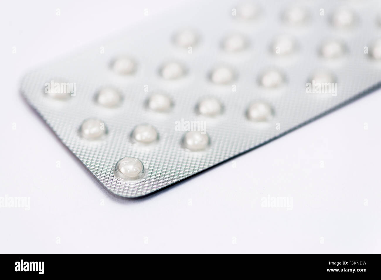 A silverish filmstrip with white medicine tablets, displayed on a white ...