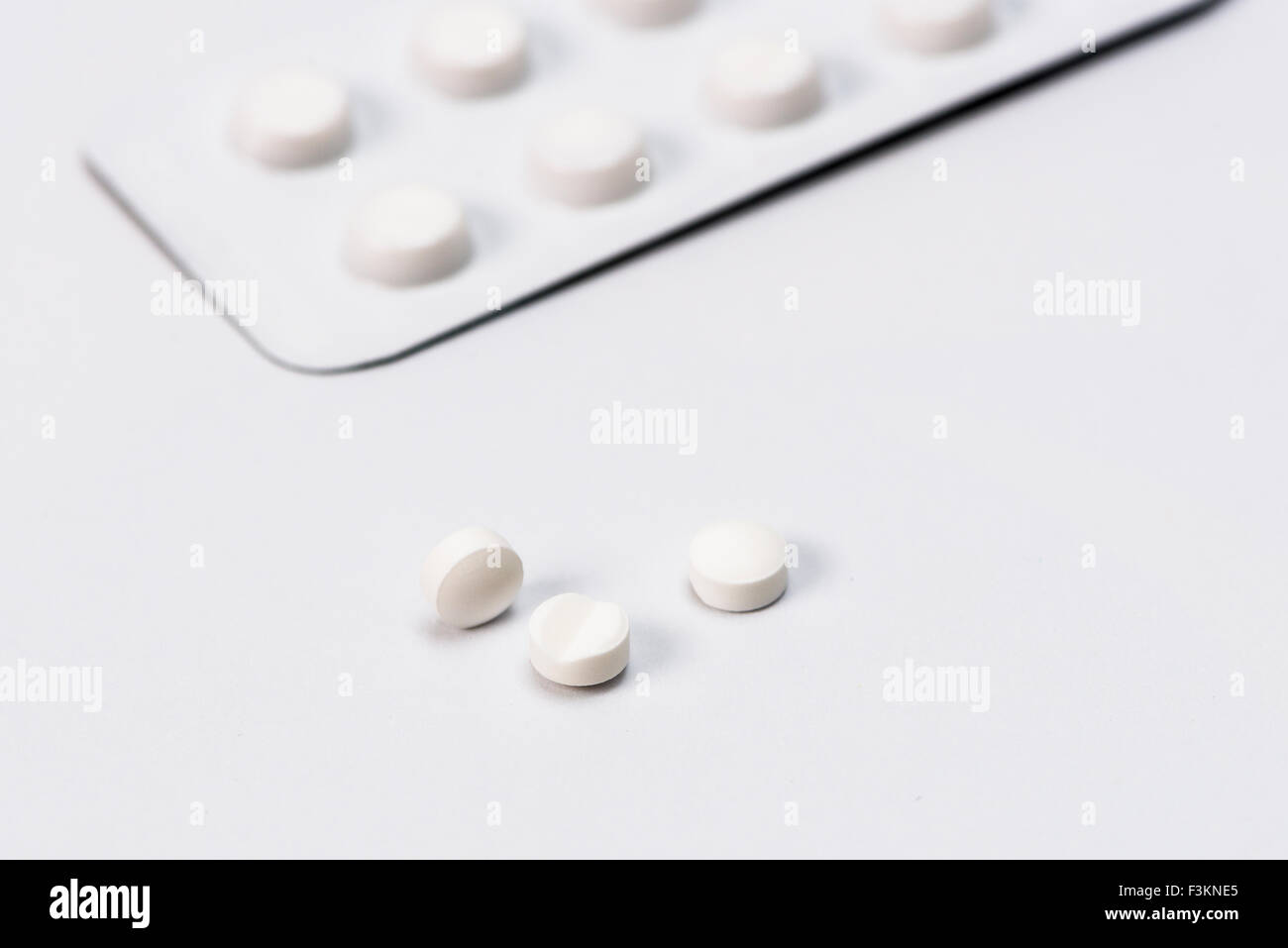 A white filmstrip with white medicine tablets, three unpacked ...
