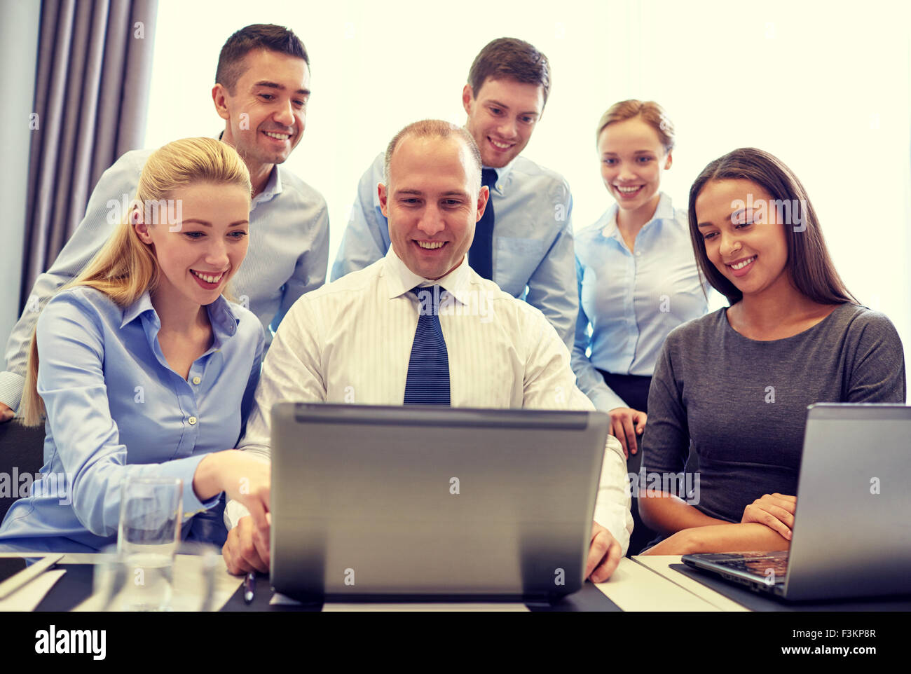 smiling business people with laptop in office Stock Photo - Alamy
