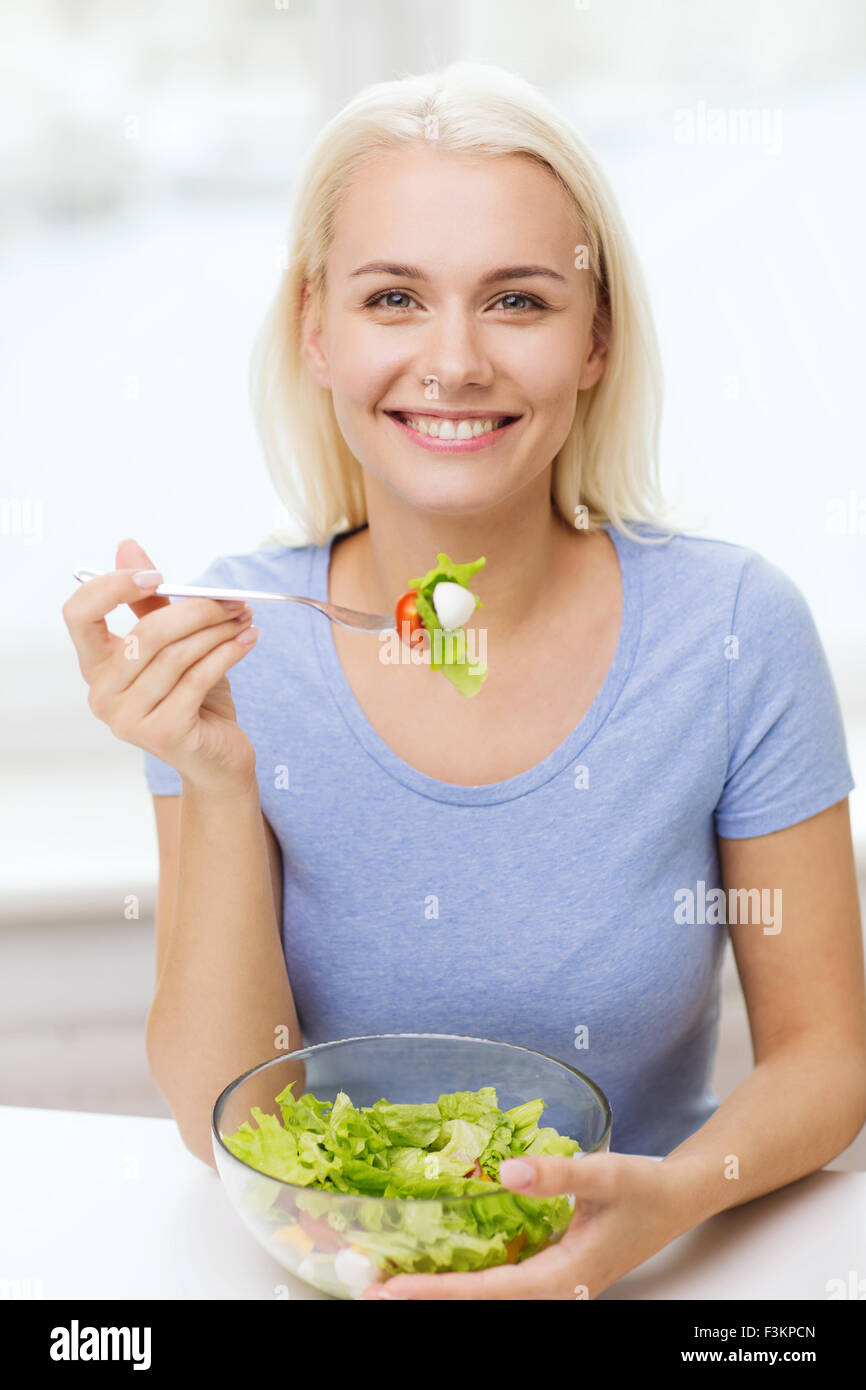 smiling young woman eating salad at home Stock Photo - Alamy