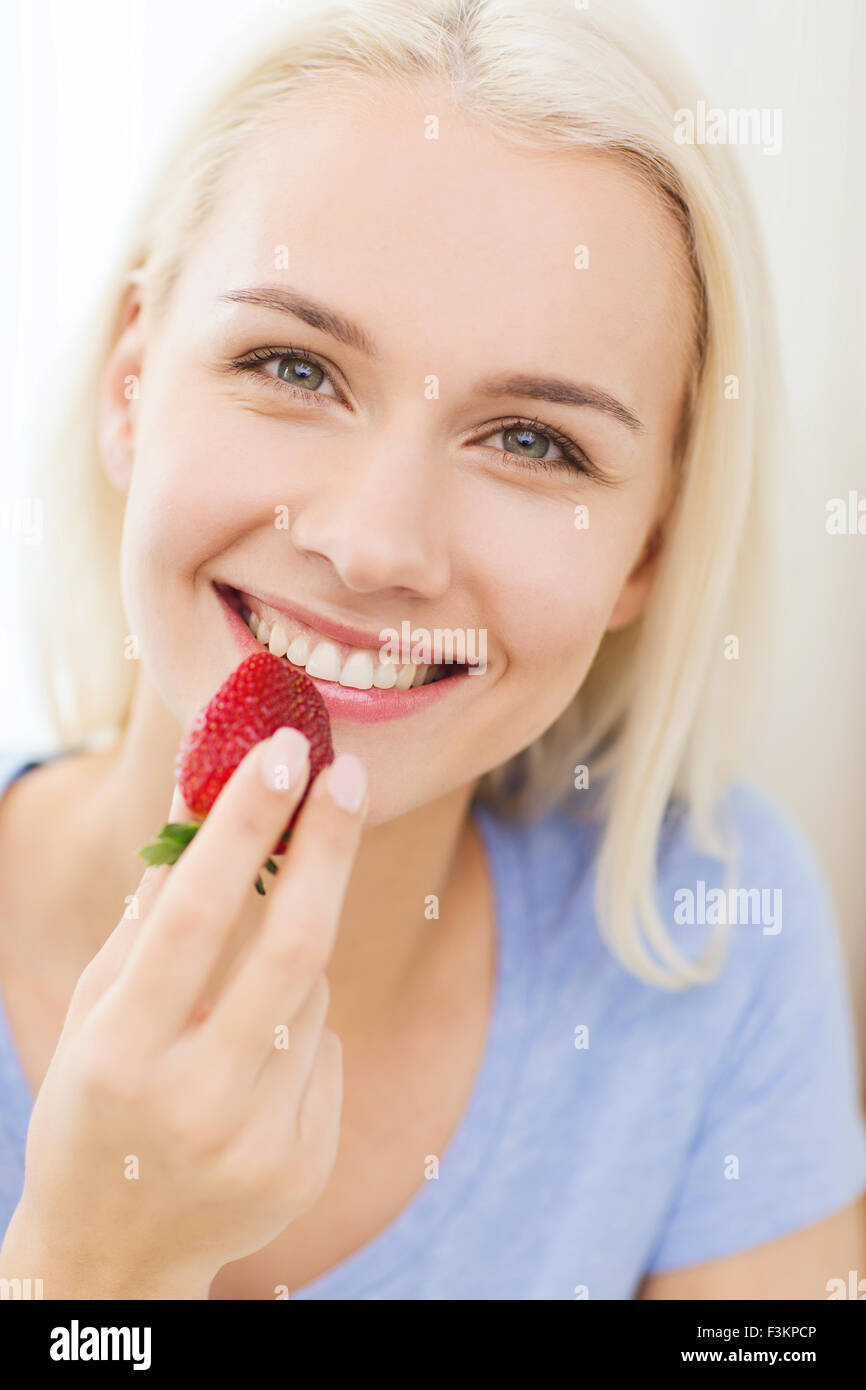 happy woman eating strawberry at home Stock Photo - Alamy