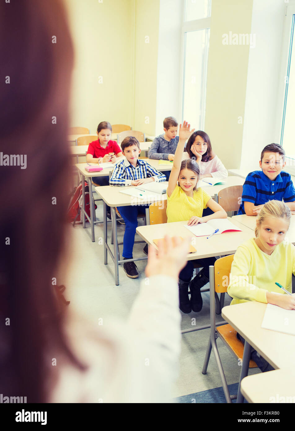 group of school kids raising hands in classroom Stock Photo - Alamy