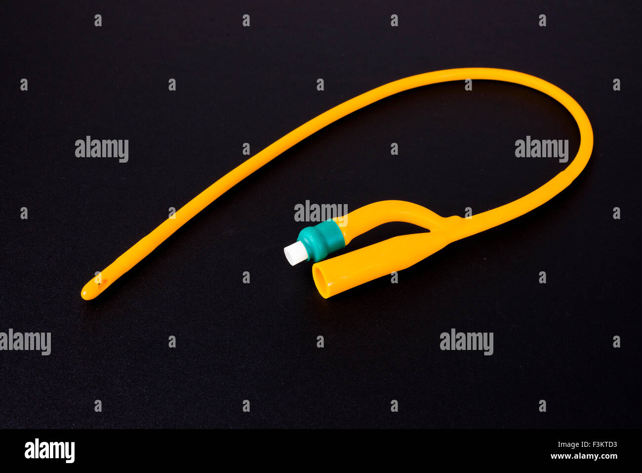 An orange balloon catheter for medical use, displayed on a black table ...