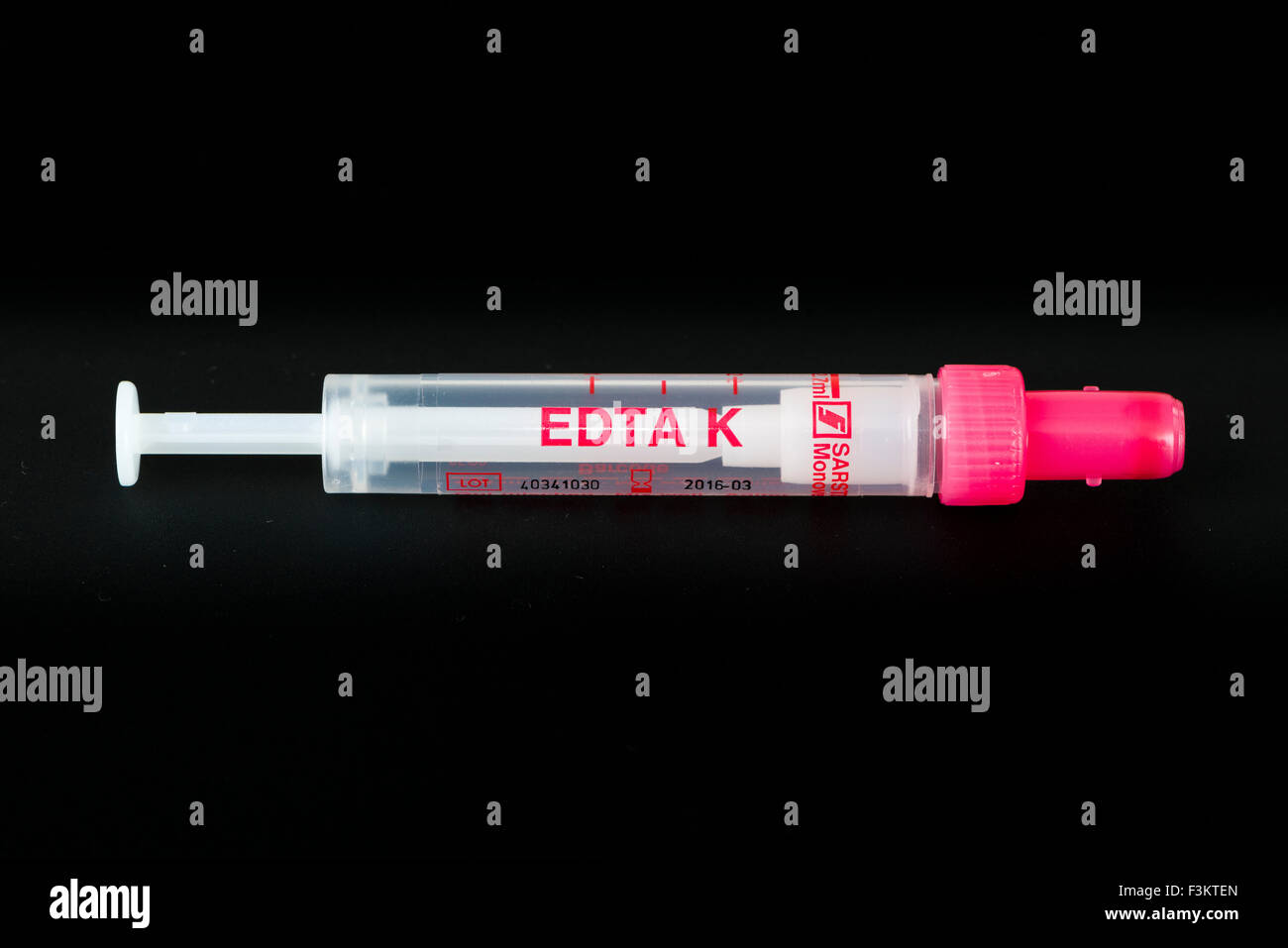 A red pharmaceutical phial for medical use, displayed on a black table ...