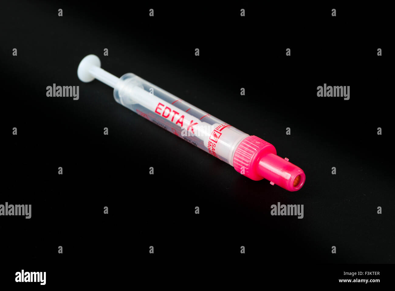 A red pharmaceutical phial for medical use, displayed on a black table ...