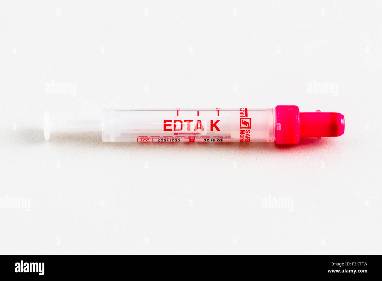 A red pharmaceutical phial for medical use, displayed on a white table ...