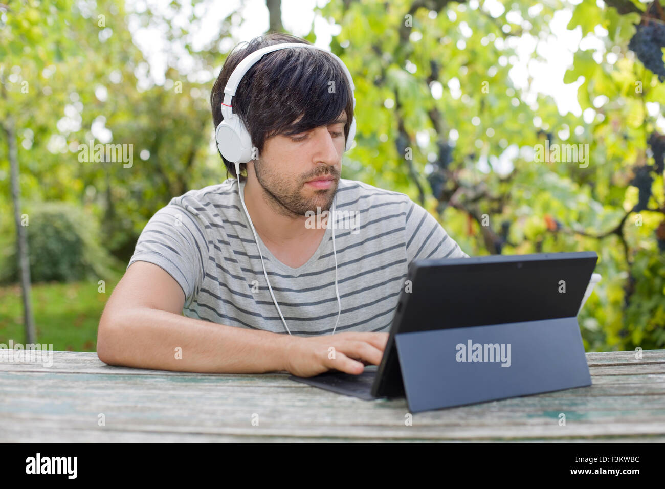 young man working with a tablet pc listening music with headphones on a ...