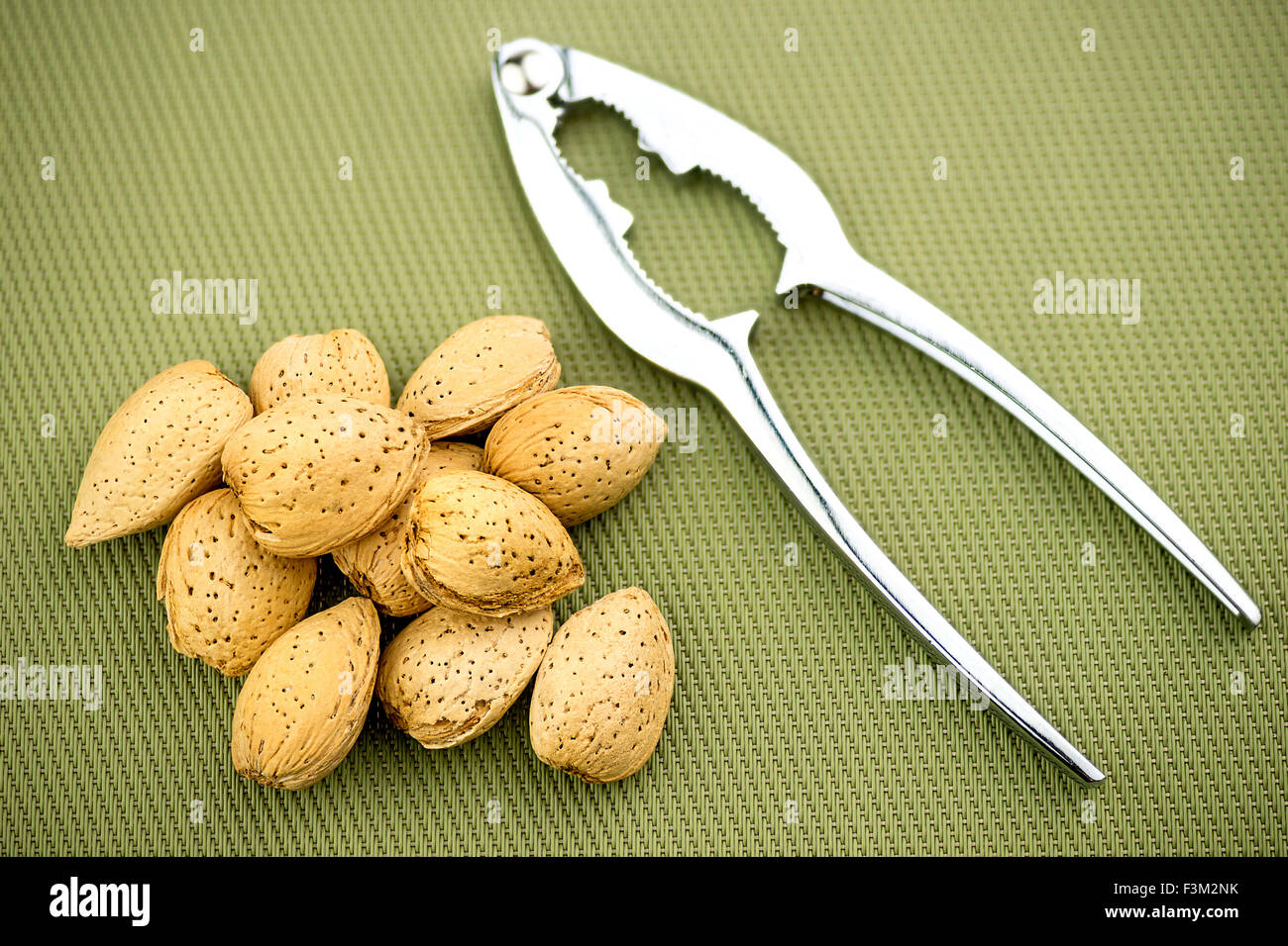 Natural almonds with shells and nut cracker Stock Photo - Alamy