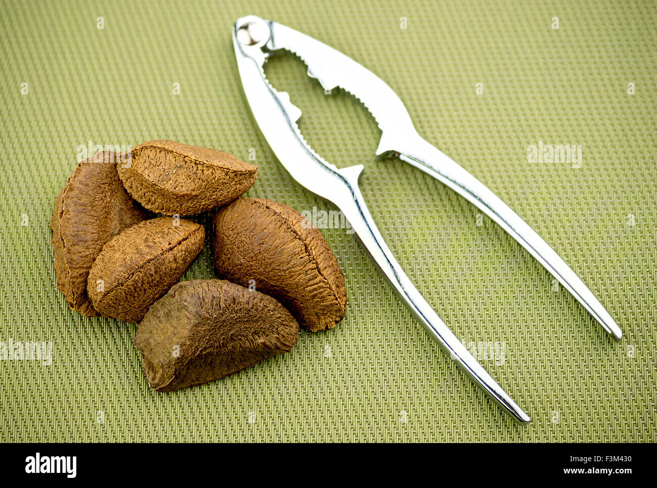 Brazil nuts with nut cracker on textured background Stock Photo - Alamy