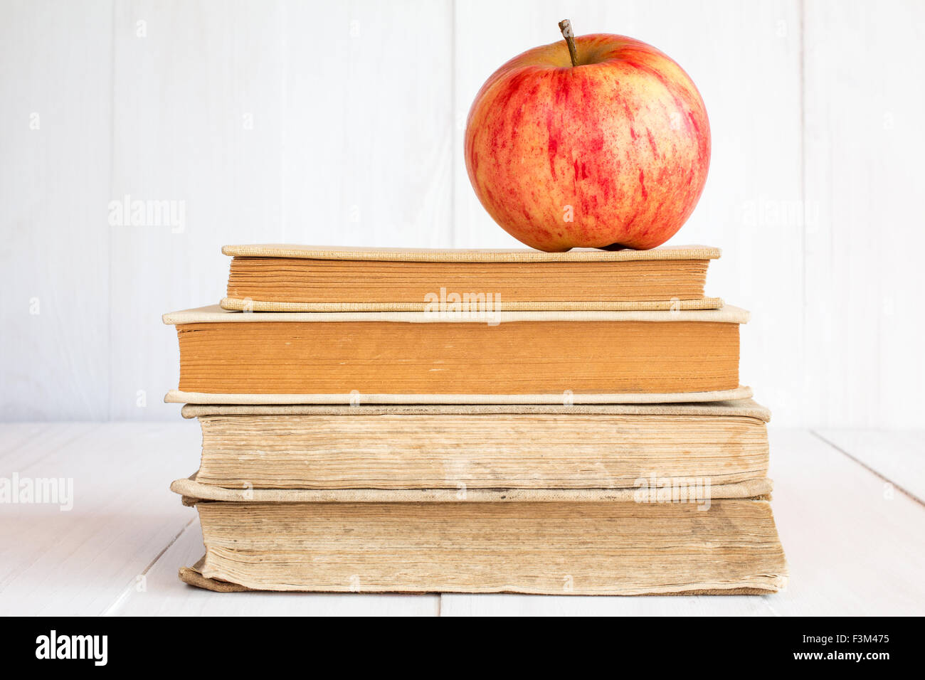 Stack of books with red apple on white wooden background Stock Photo ...