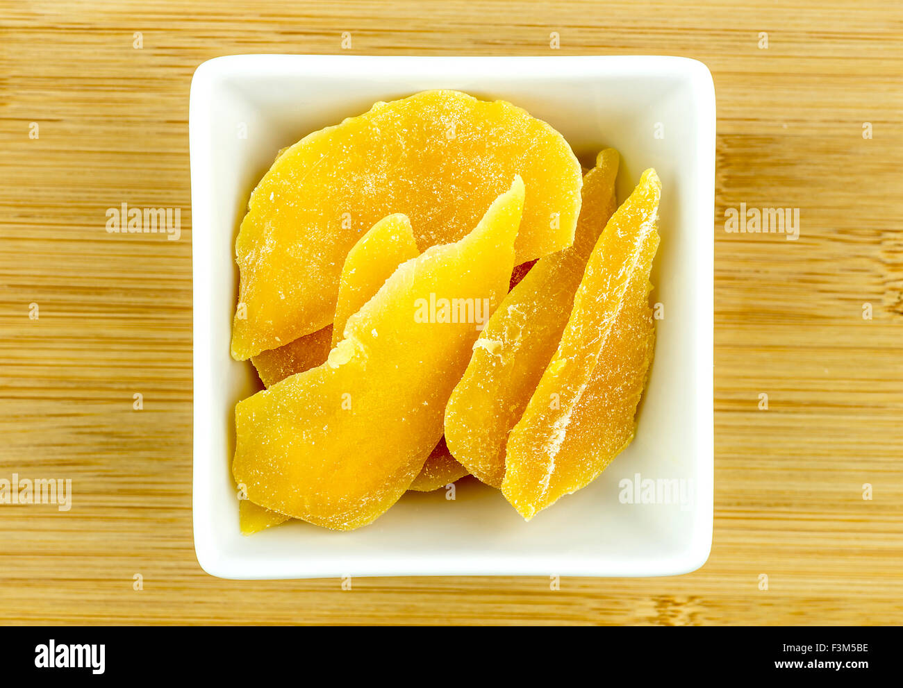 Dehydrated dried mango in white bowl on wooden background Stock Photo ...