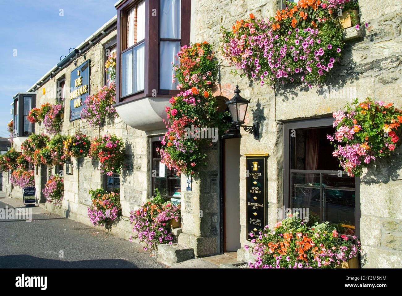 Porthleven, Cornwall, UK. harbourside pub with flowers in hanging ...