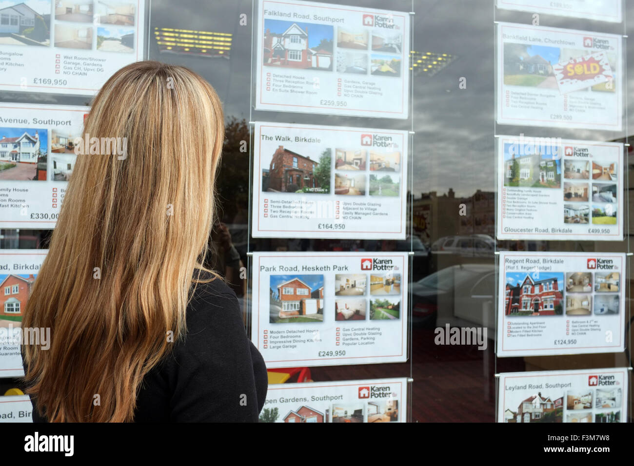 A woman looking estate agents window at domestic houses for sale on the ...