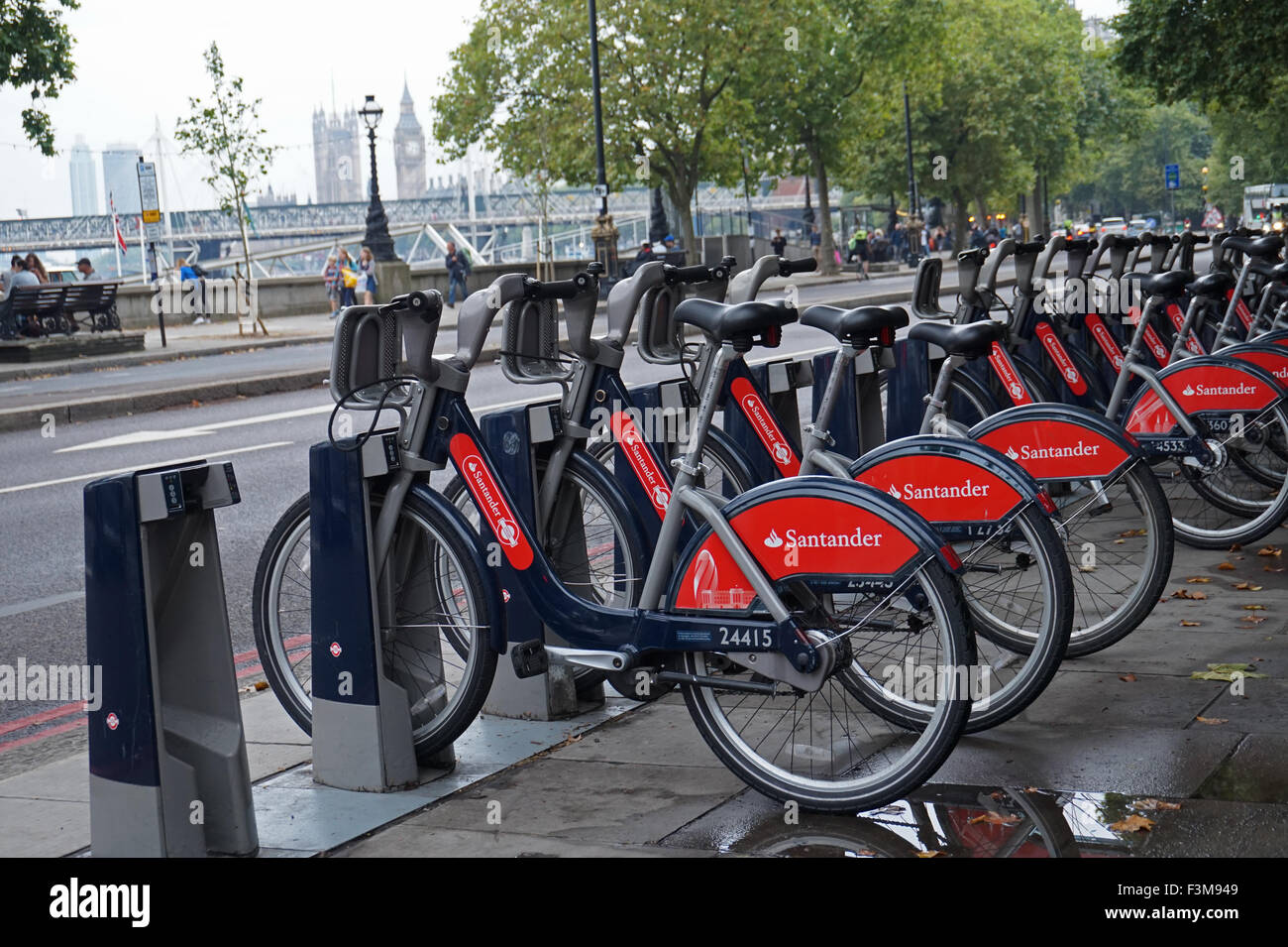 "Boris" bikes on their stands with the Houses of Parliament behind, Embankment, London, England ...