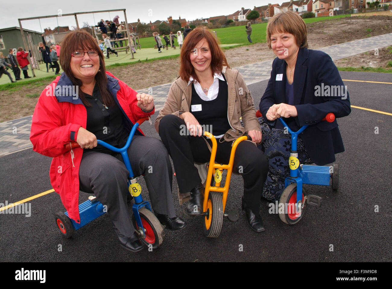Three (3) women teachers having fun riding childrens small cycles at ...