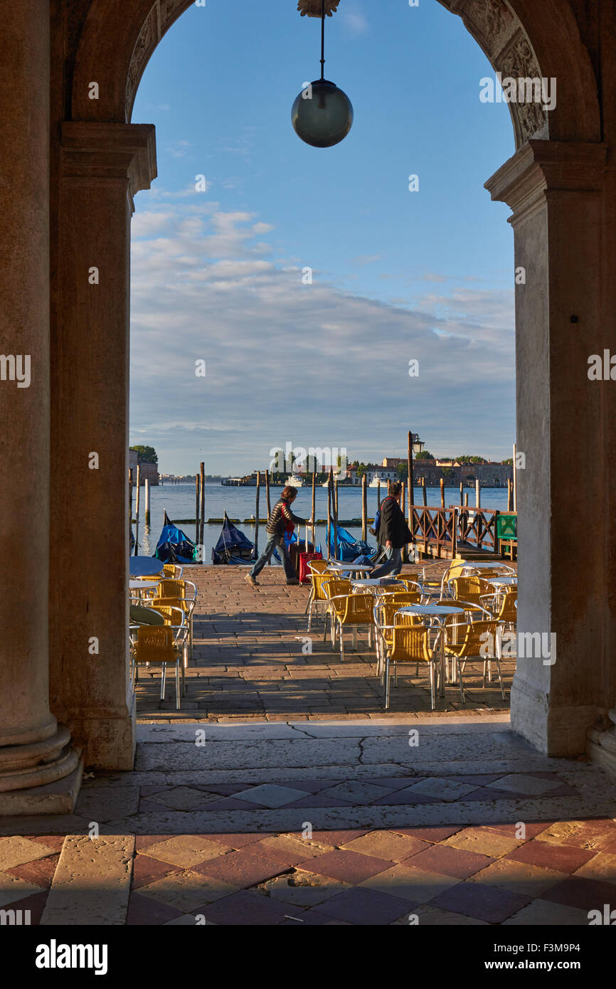 Tourists wheeling suitcases along waterfront at sunrise seen from ...