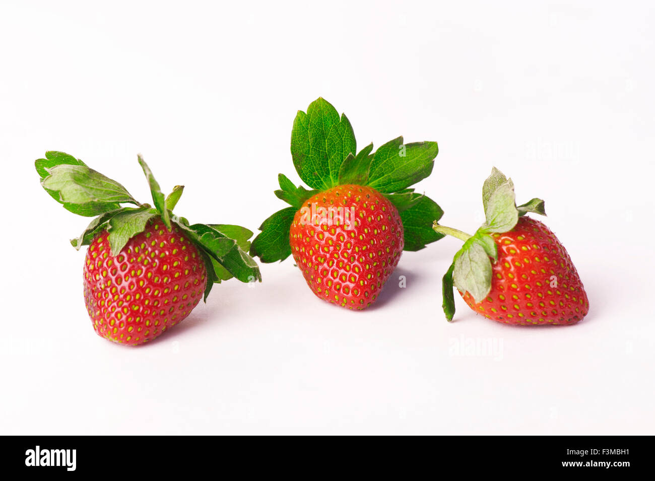 Three Strawberries with isolated white background Stock Photo - Alamy