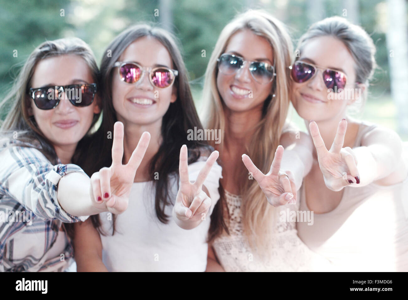 Happy smiling girlfriends showing a v hand sign Stock Photo - Alamy