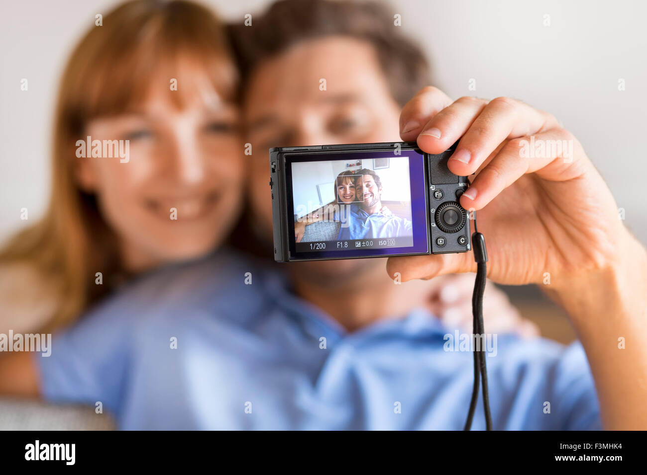 Cheerful couple taking a selfie with a camera. White home background ...