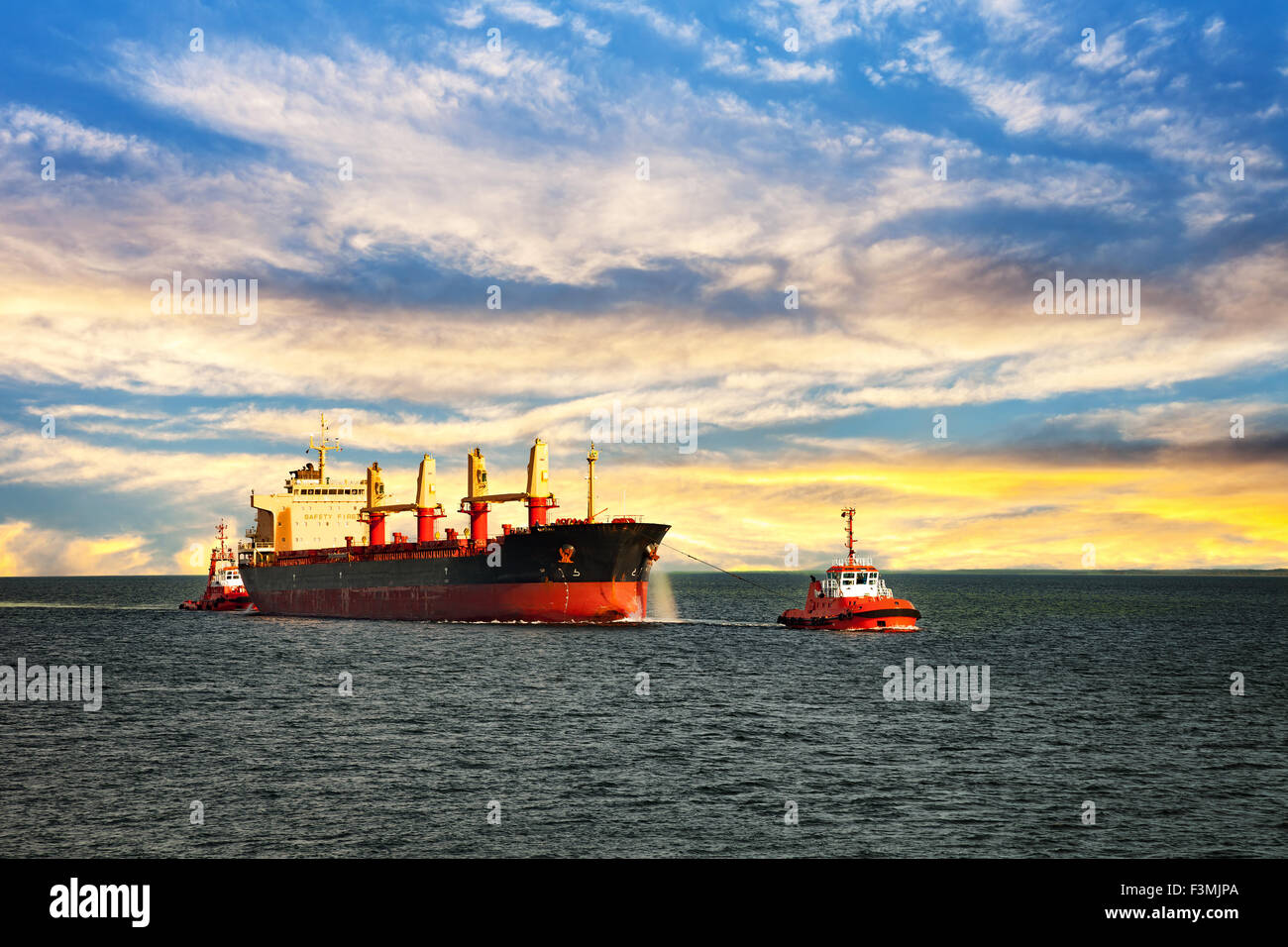 Tugboats assisting cargo ship sea in the morning Stock Photo - Alamy