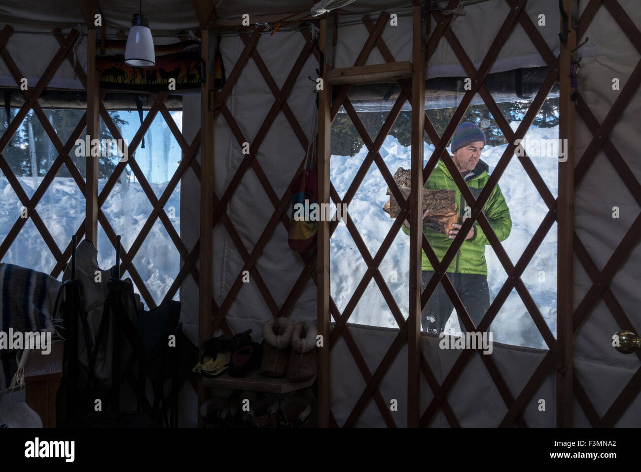 A man carrying an armload of firewood into a yurt, Red Mountain Pass ...