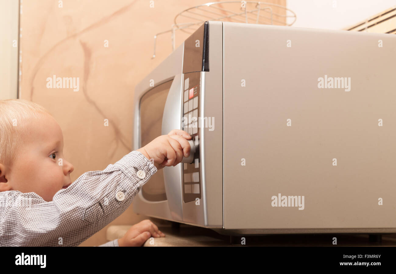 Childhood. Little boy child kid playing with timer of microwave oven ...