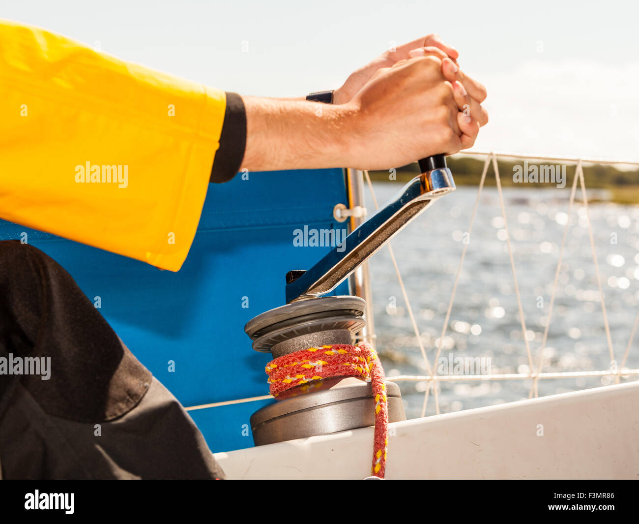 Male hand on winch capstan with rope on sailing boat. Yachting yacht in ...