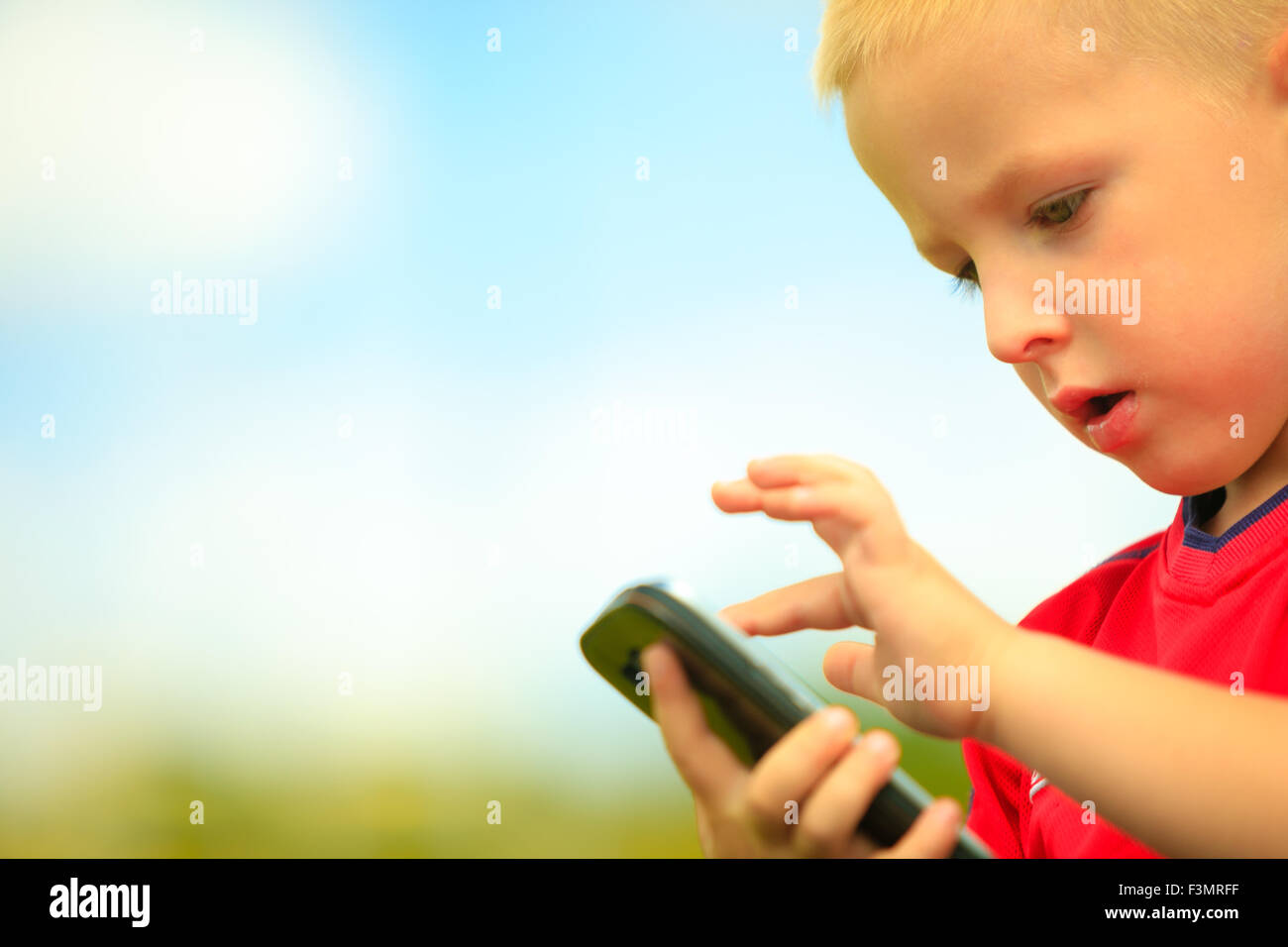 Little boy child kid playing games on smartphone mobile phone outdoor ...