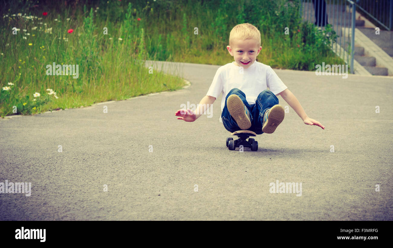 Child sitting on skateboard outdoor. Active boy skateboarding on ...