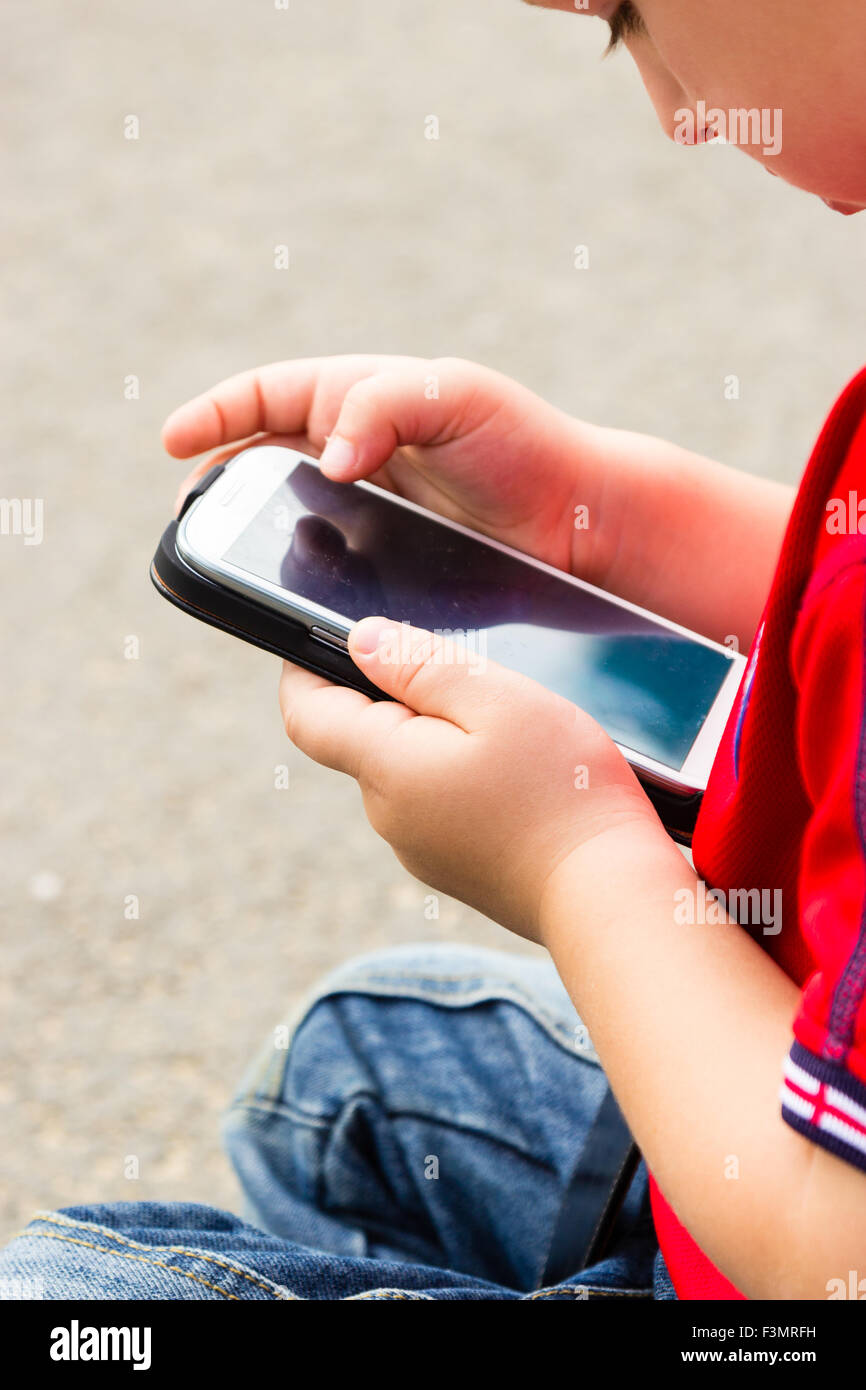 Little boy child kid playing games on smartphone mobile phone outdoor ...