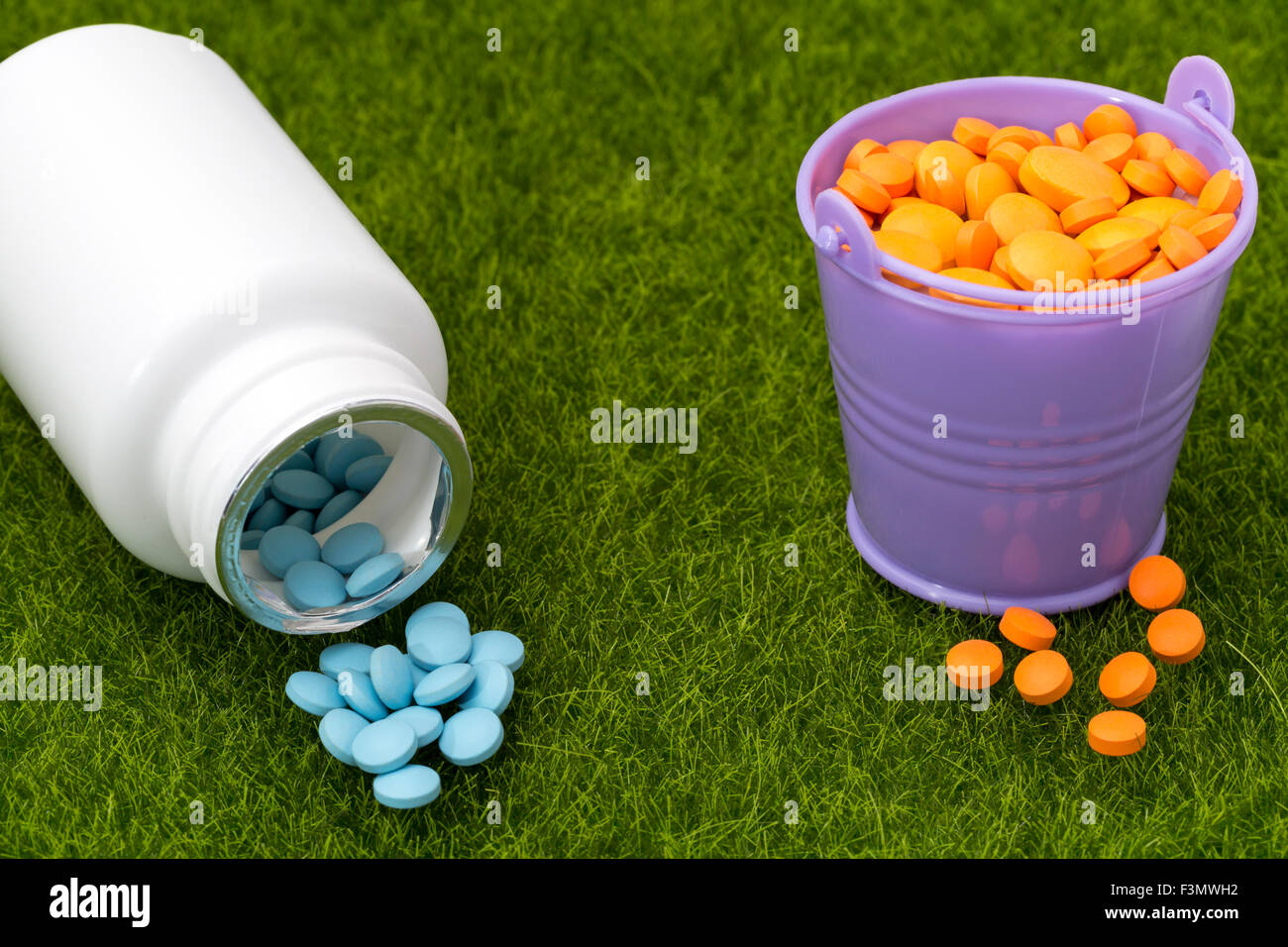 White bottle of blue pills and buckets filled with orange tablets on ...