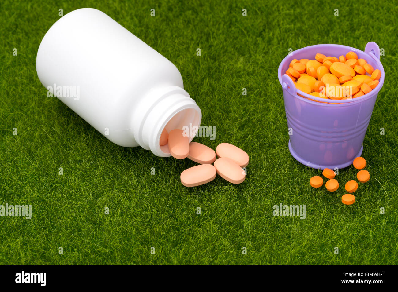 White bottle of orange pills and buckets filled with colorful pills on ...
