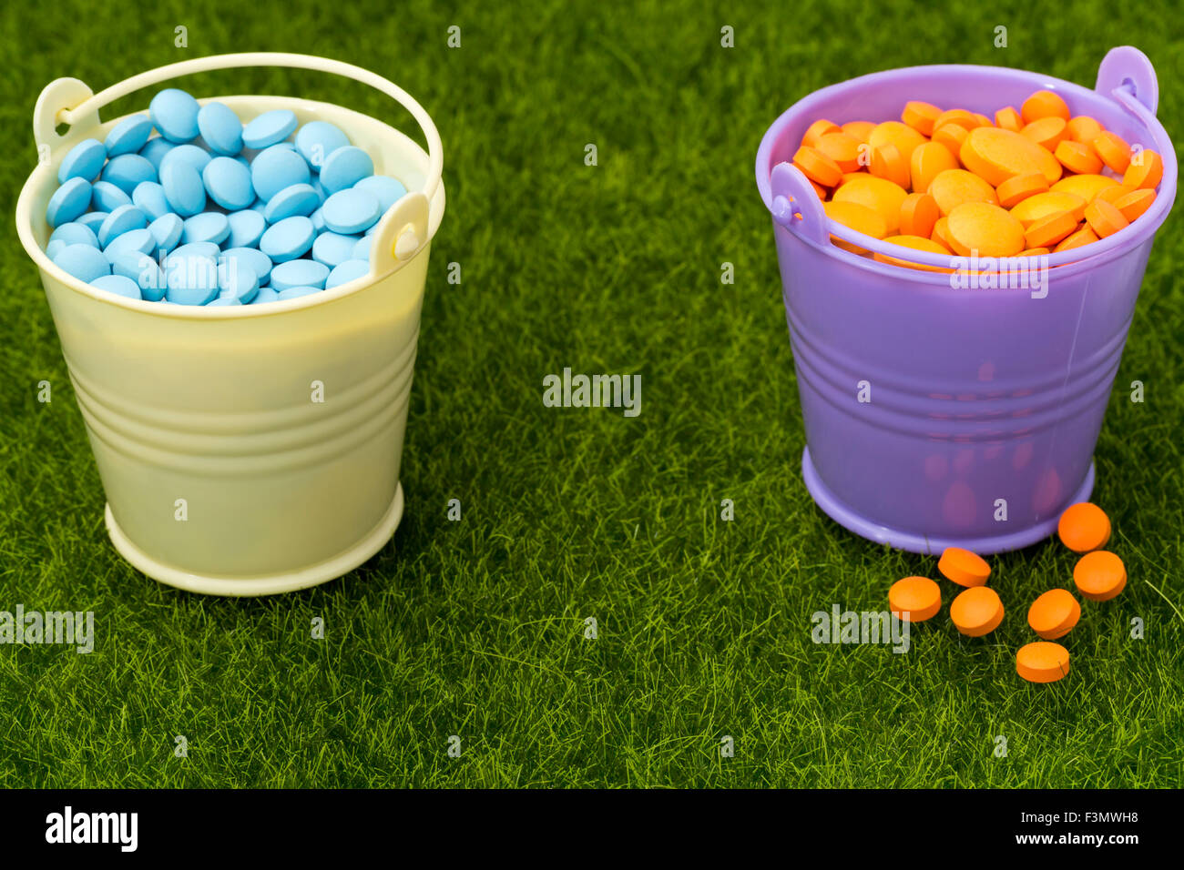 Pharmaceutical concept. Two buckets filled with orange and blue pills ...