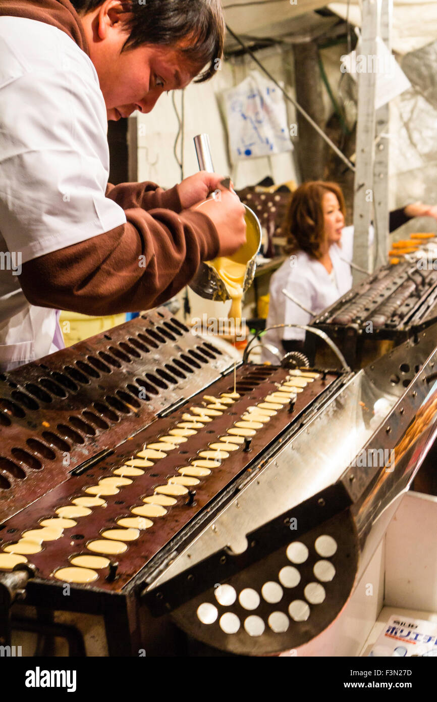 Japanese festival food. Man at fast food stall making takoyaki, octopus ...