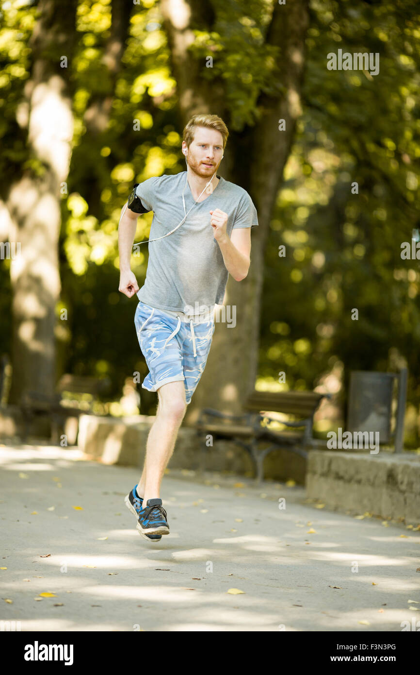Young man running in the autumn park Stock Photo - Alamy