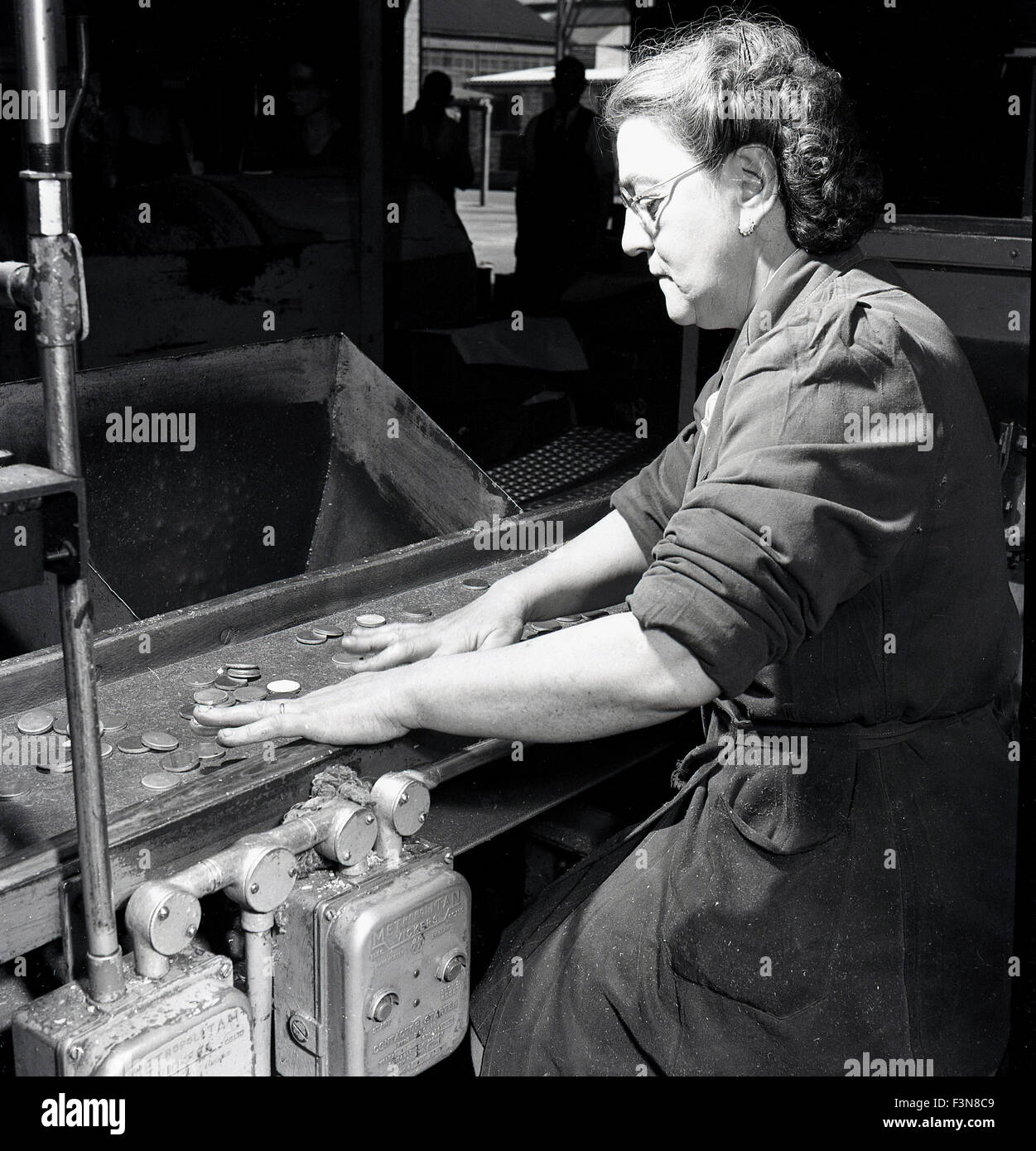 1950s, histriorical, a female operative checking parts on a conveyor ...