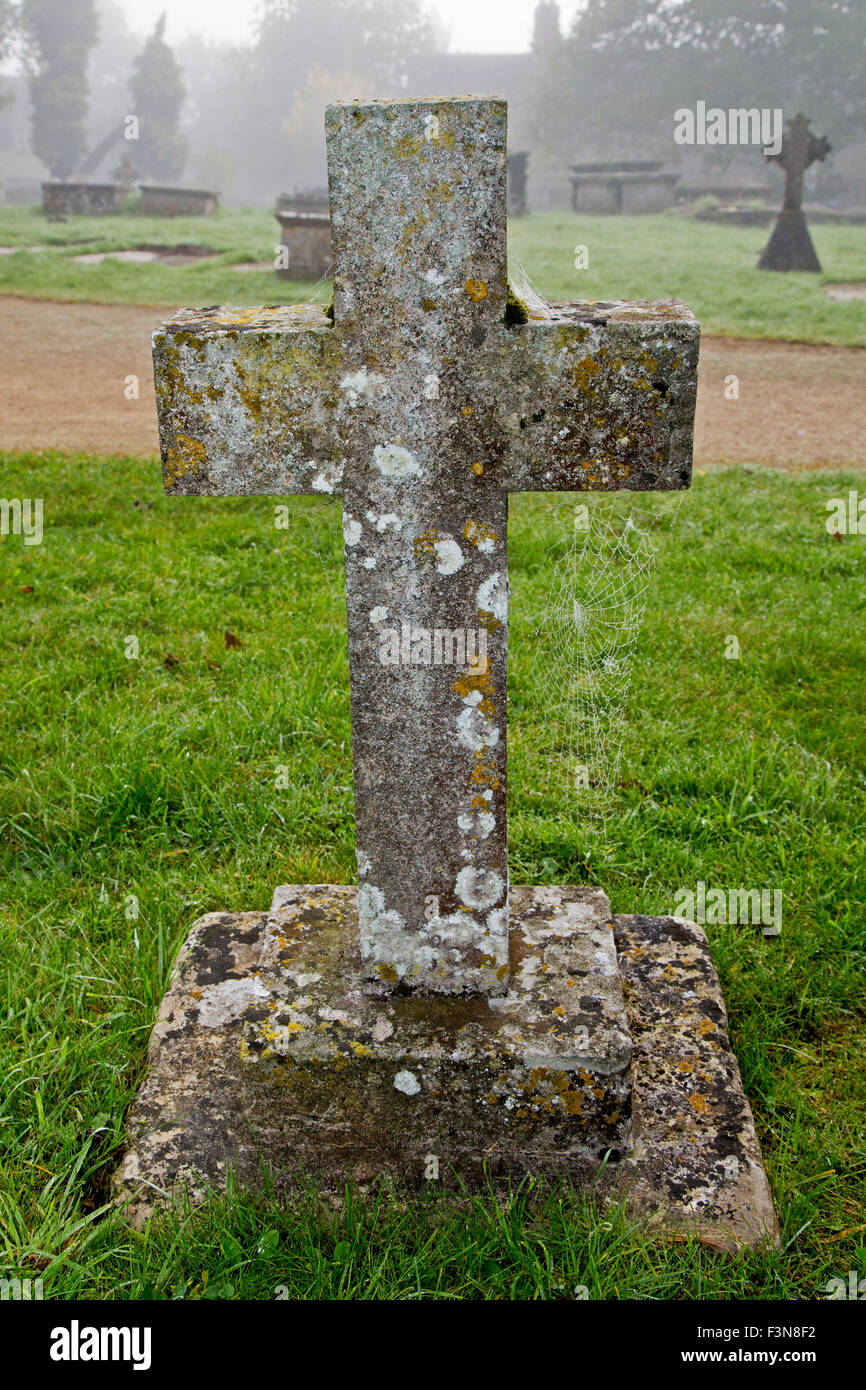 A gravestone in the form of a cross, covered in spider's web at St Mary ...