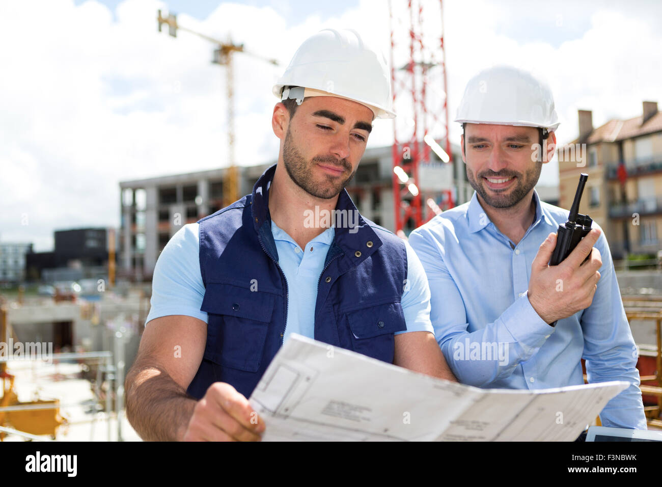 View of a Engineer and worker watching blueprint on construction site ...