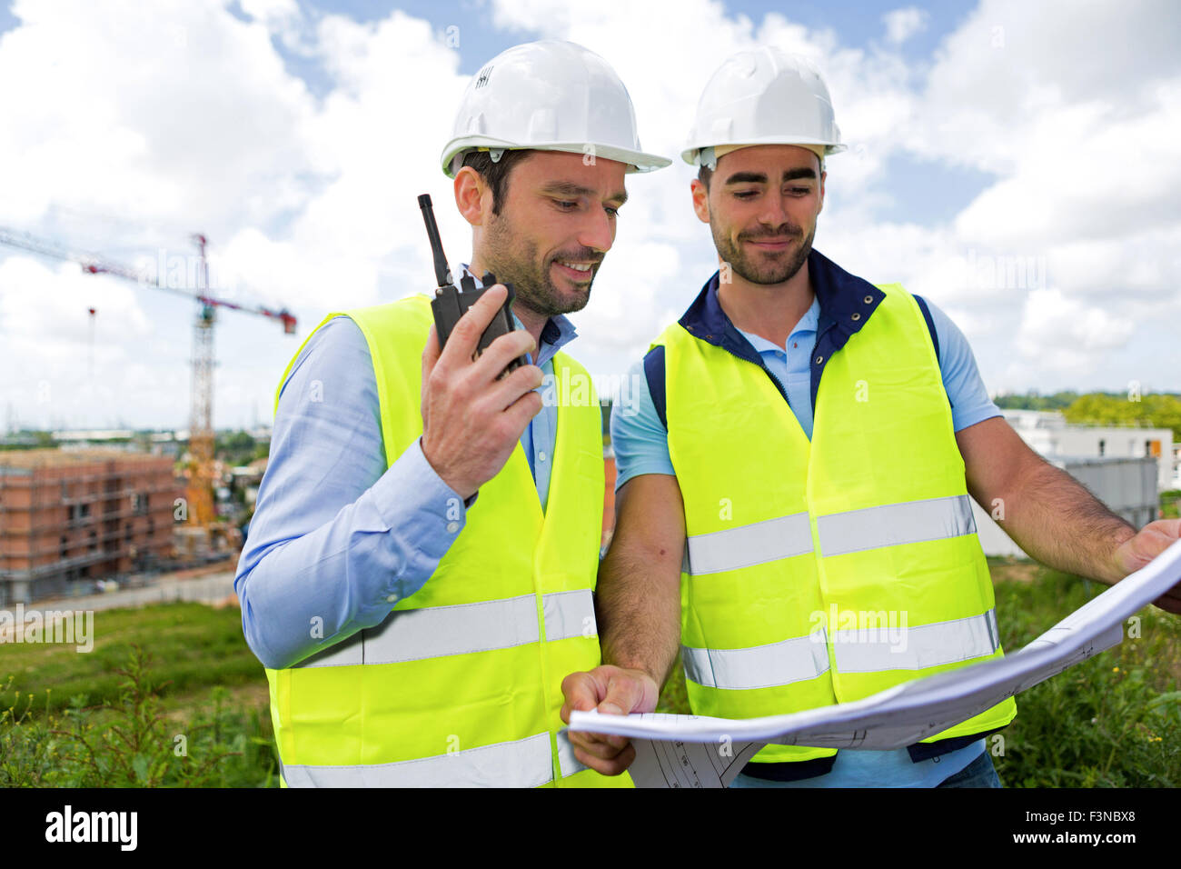 View of a Engineer and worker watching blueprint on construction site ...