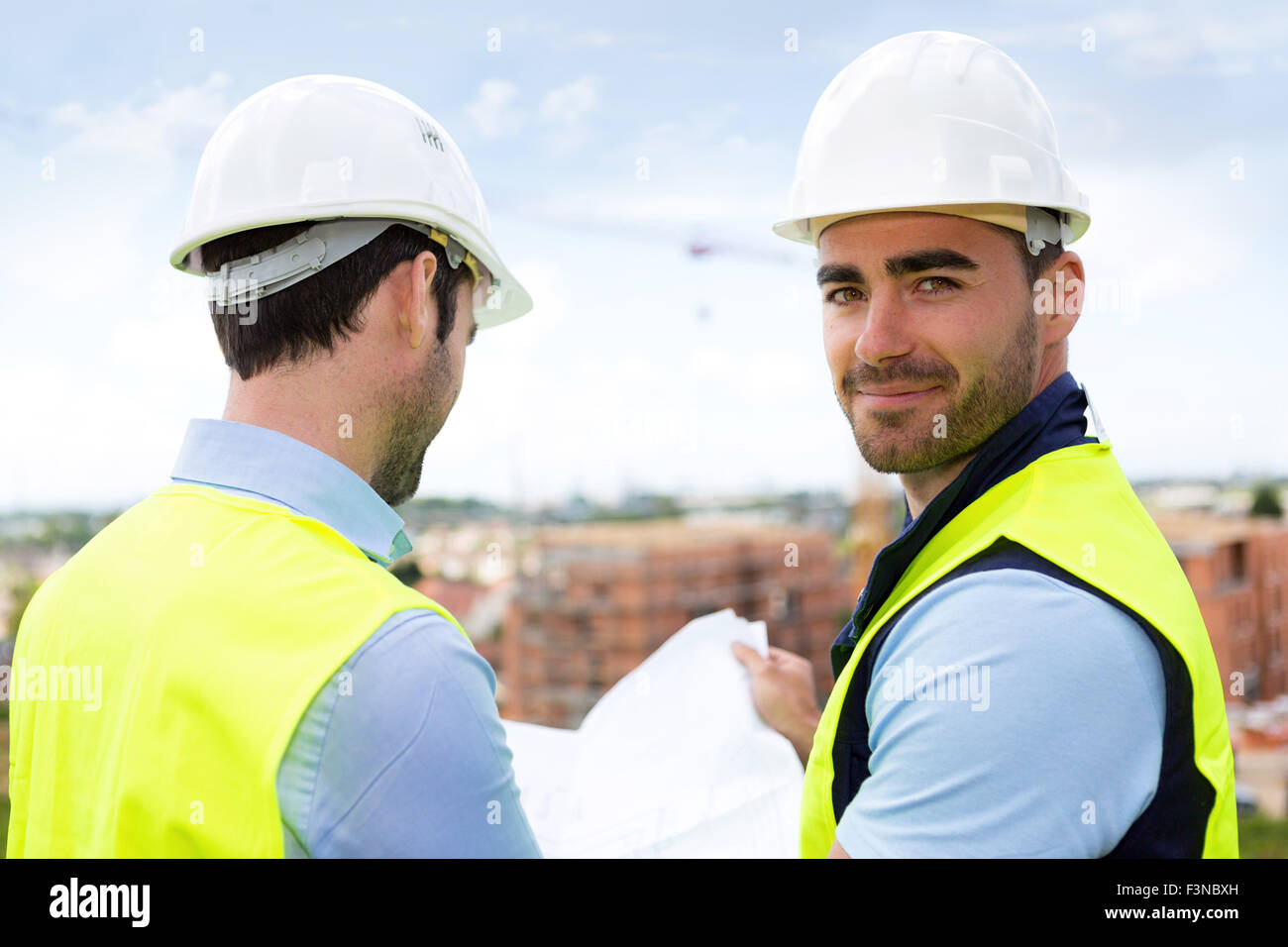 View of a Engineer and worker watching blueprint on construction site ...