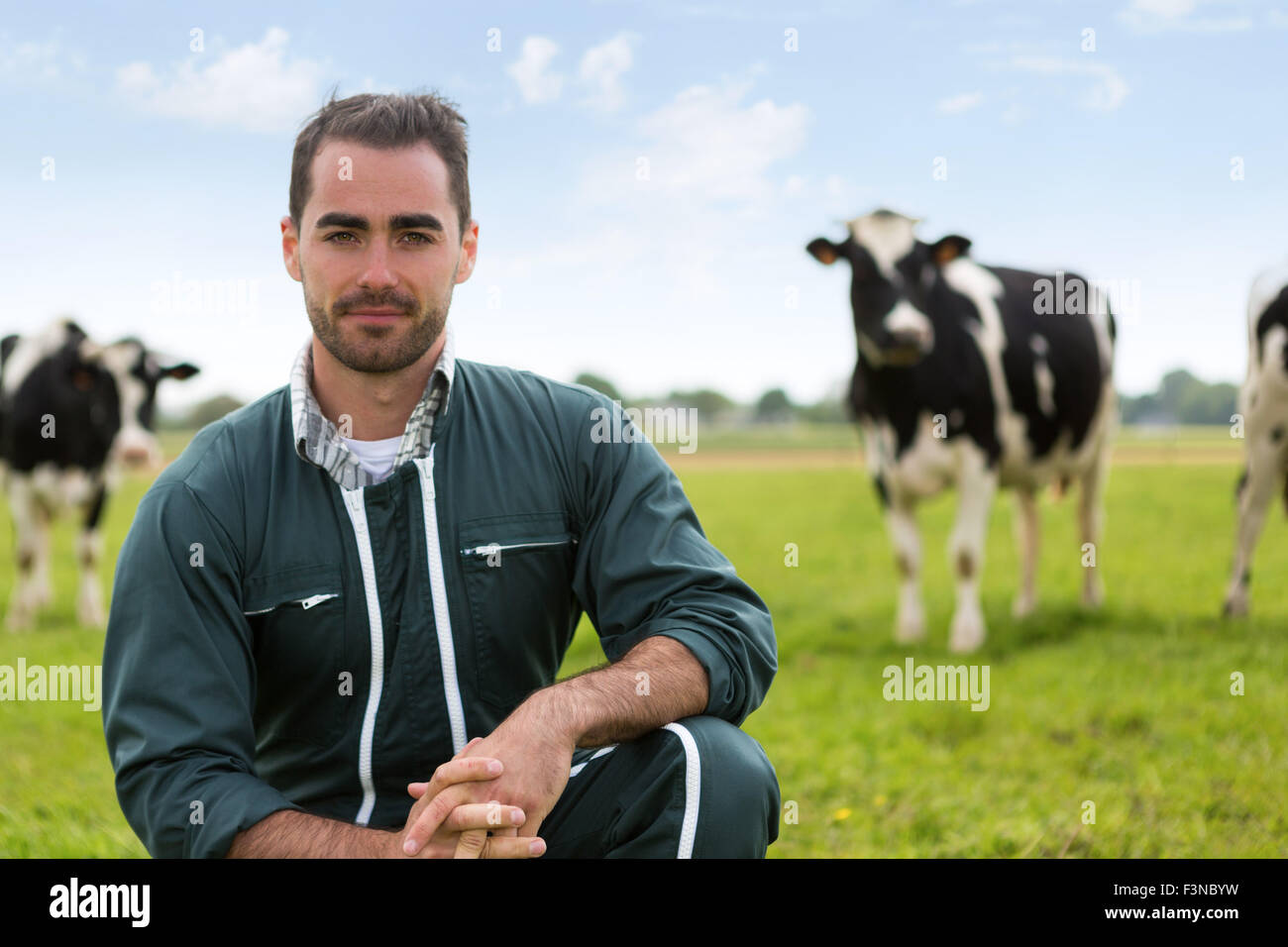 View of a young attractive farmer in a pasture with cows Stock Photo ...