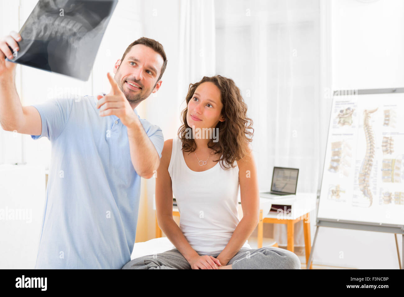 View of a Young attractive physiotherapist analysing X-ray with patient ...