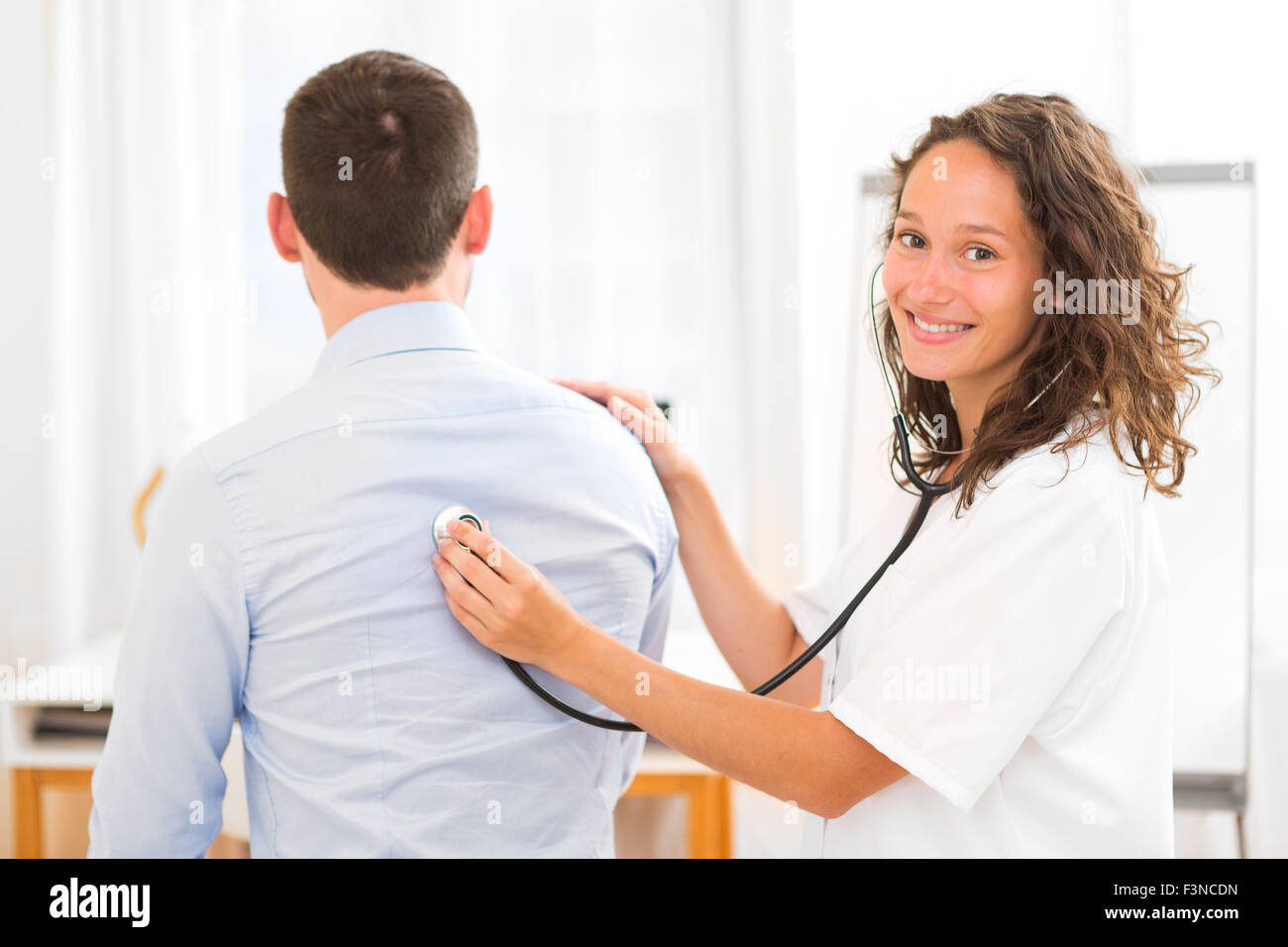 View of a Young attractive doctor checking patient's heart beatment ...