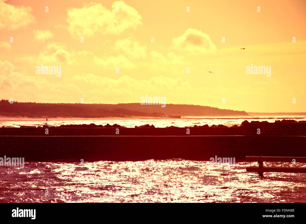 Coast and nature. Sunset over sea with jetty bathed in the sun rays ...