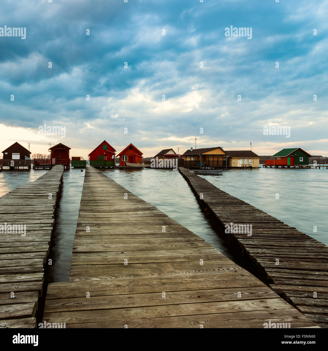 Sunset lake Bokod with pier and fishing wooden cottages, power plant in ...